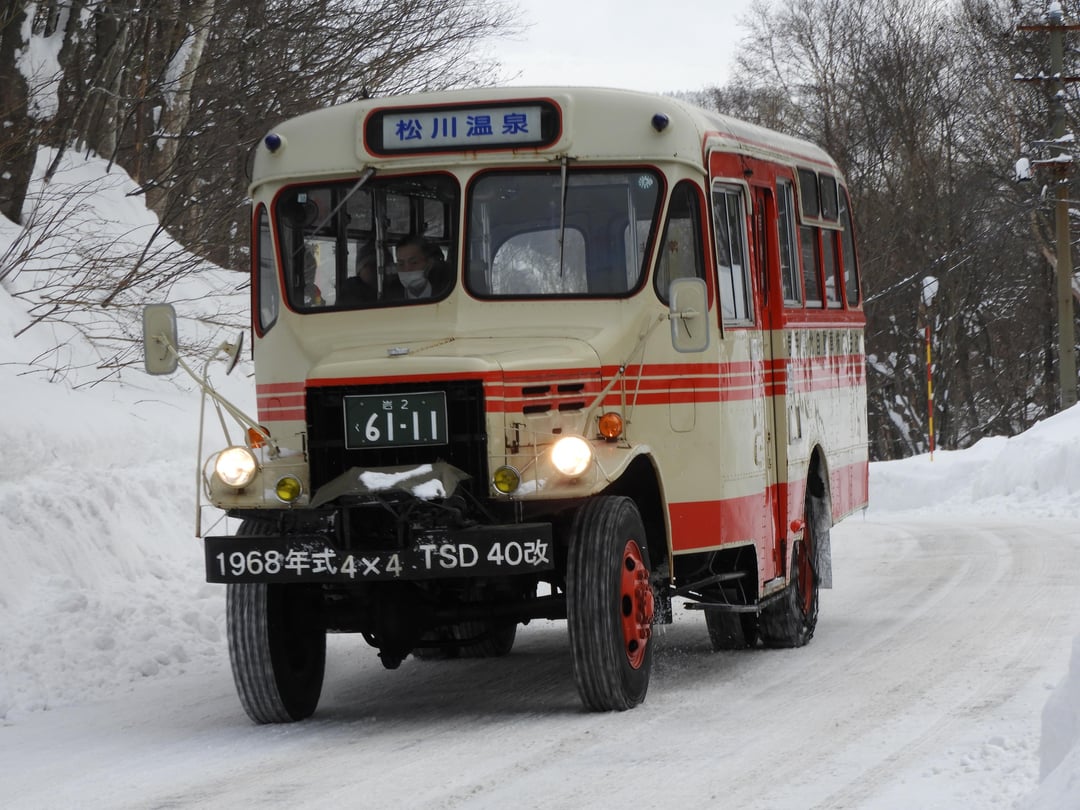 A classic bonnet-style transit bus running through the snowy mountains ...